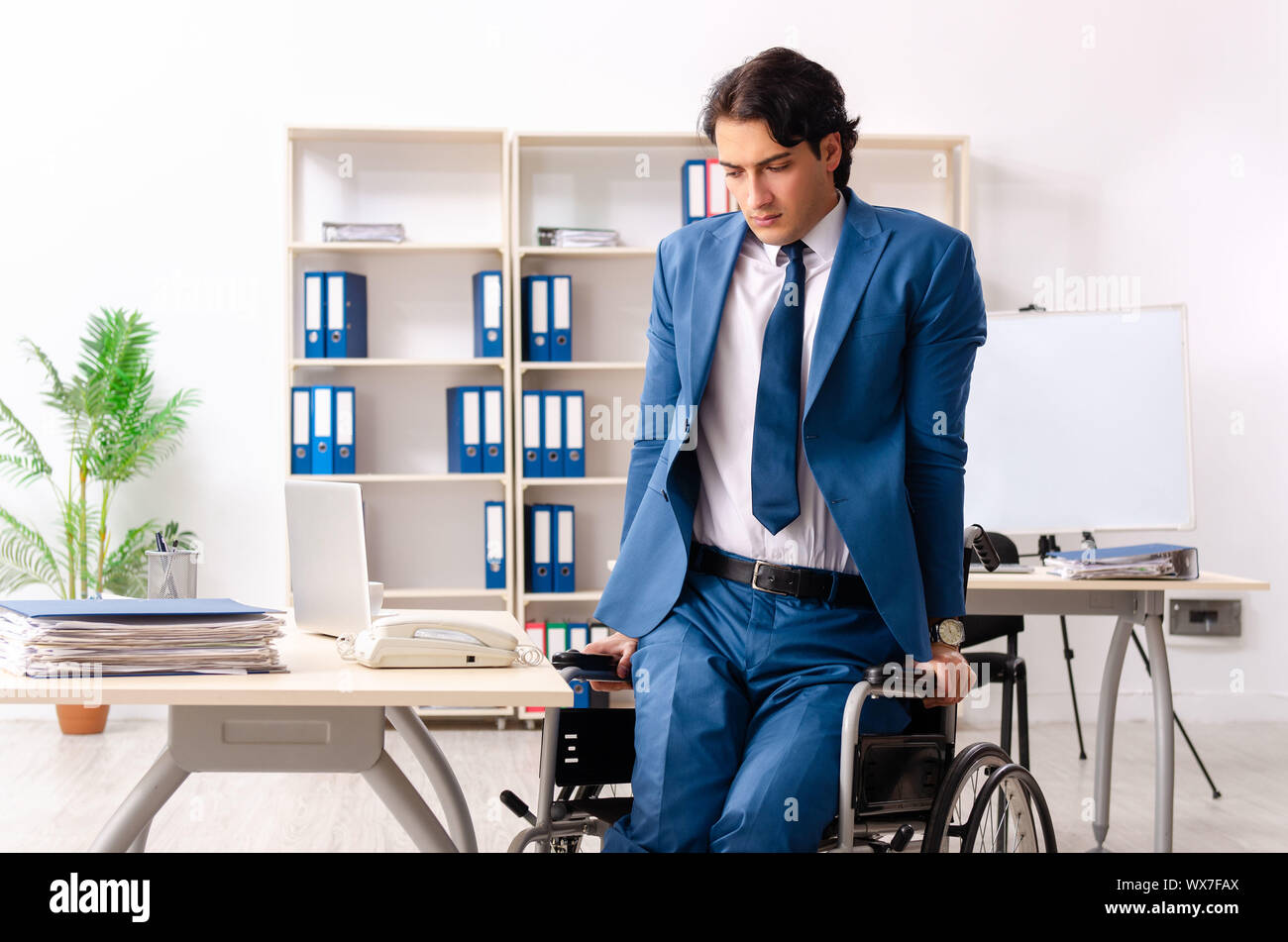 Male employee in wheelchair working at the office Stock Photo - Alamy
