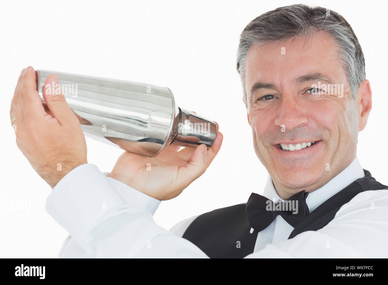 Happy waiter in suit shaking drink in cocktail shaker on white ...