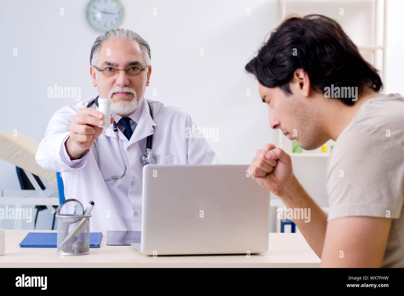 Young man visiting old male doctor Stock Photo - Alamy