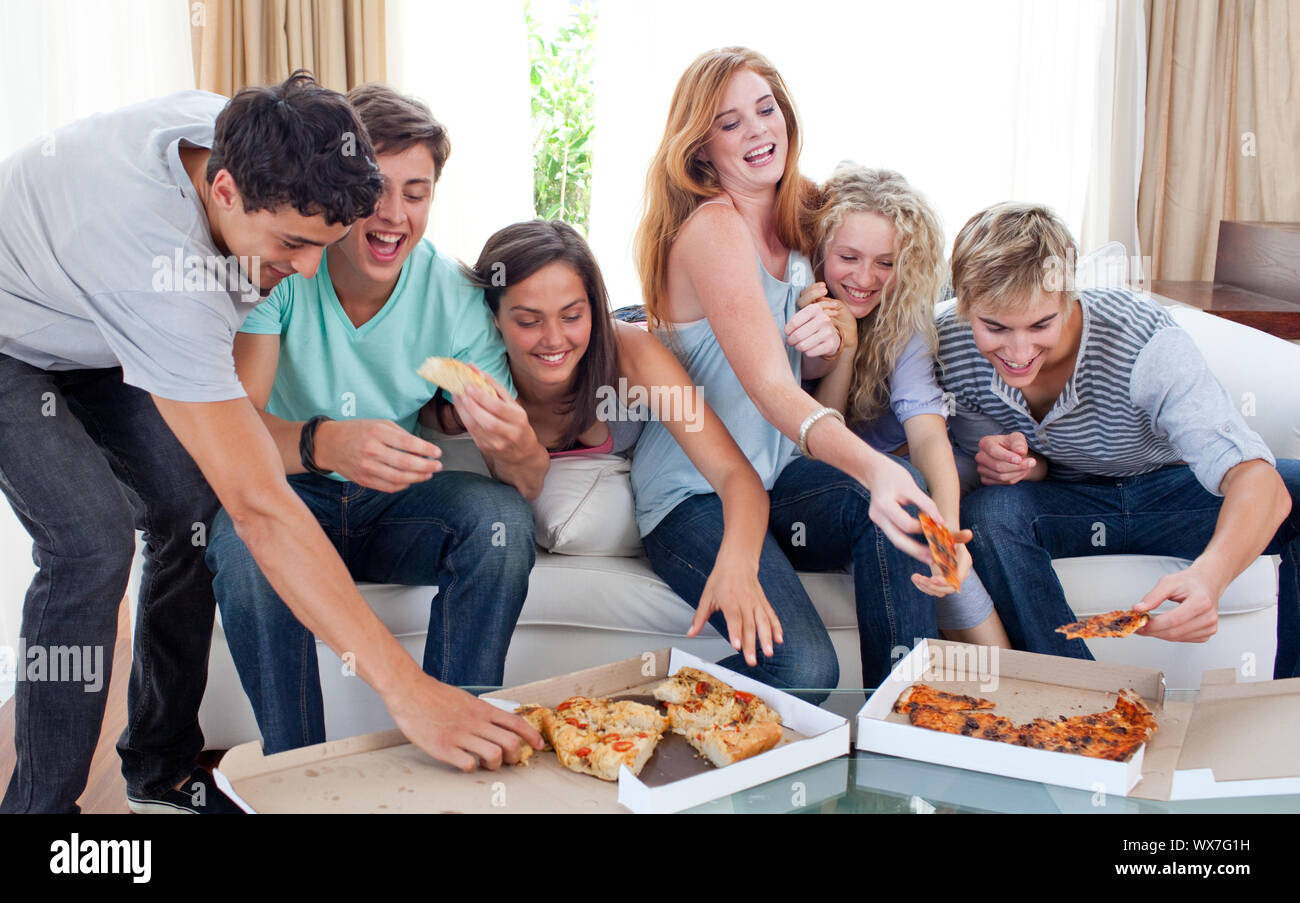 Six friends eating pizza in the living-room on the sofa Stock Photo - Alamy