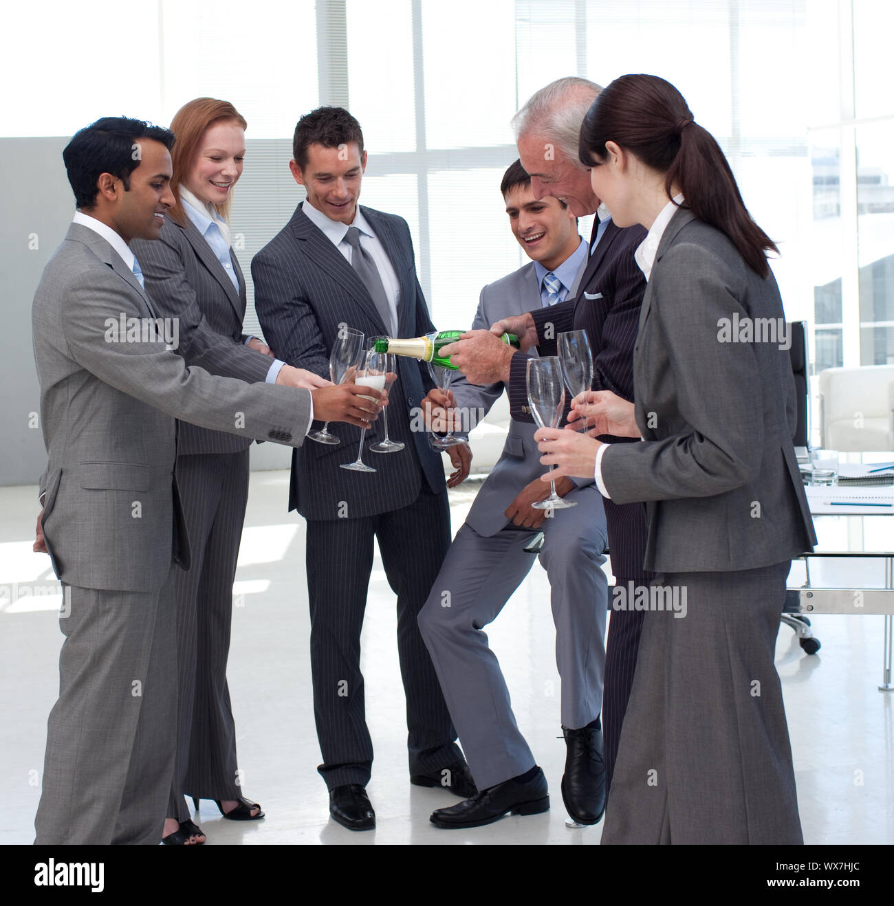 Successful businessman serving Champagne to his colleagues after a ...