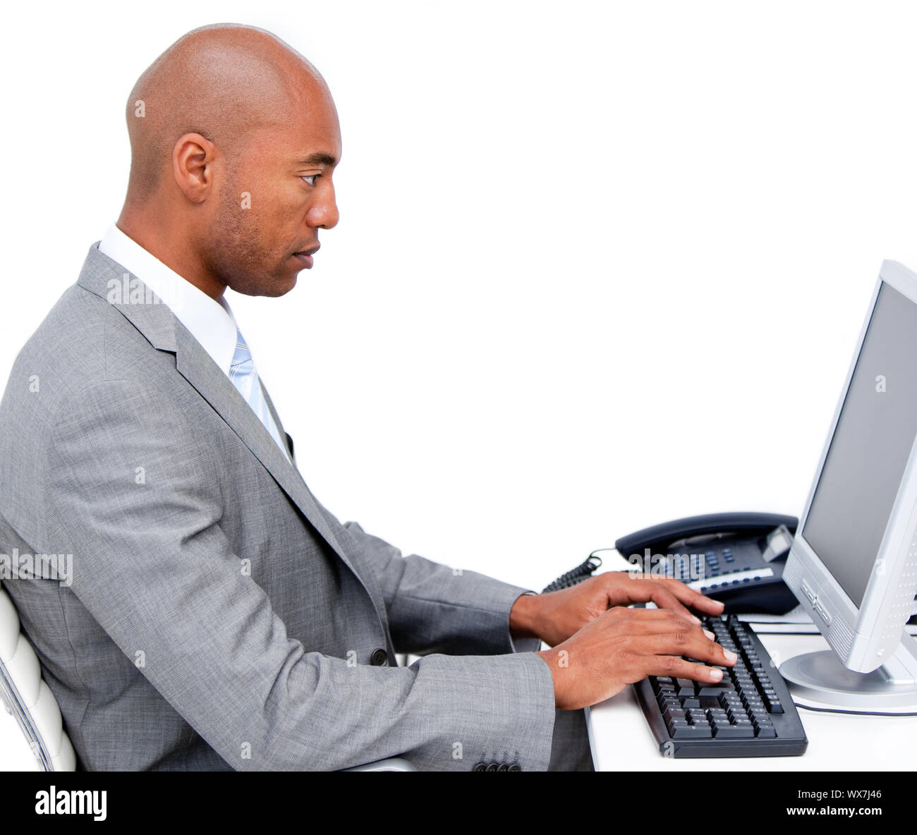 Serious businessman working at a computer against a white background ...