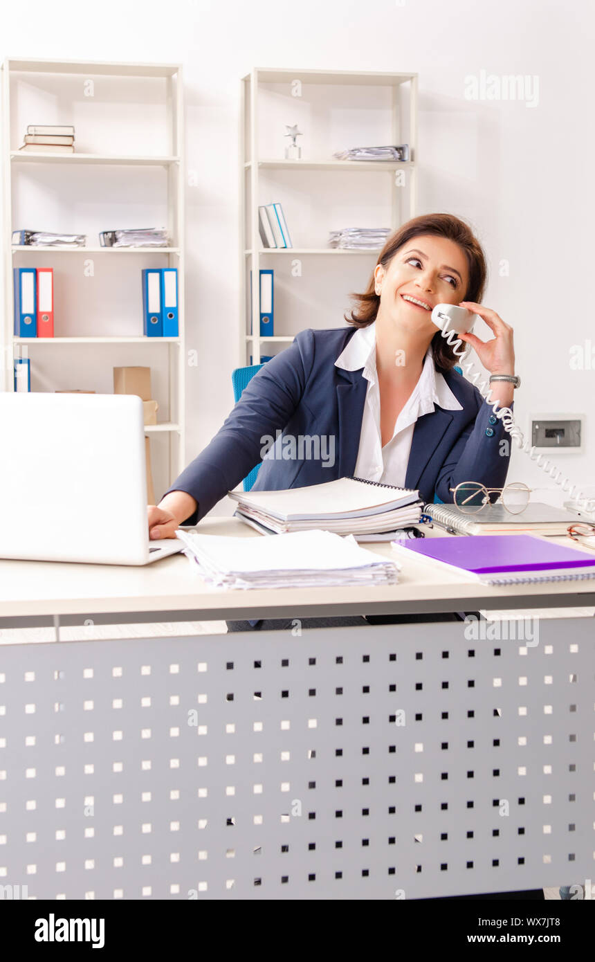 Middle-aged female employee sitting at the office Stock Photo - Alamy