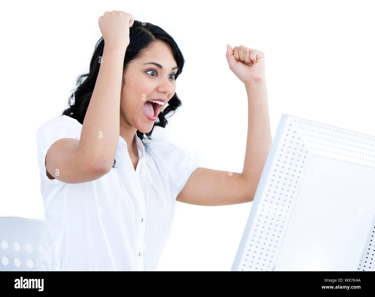 Enthousiastic businesswoman punching the air in front of her computer ...