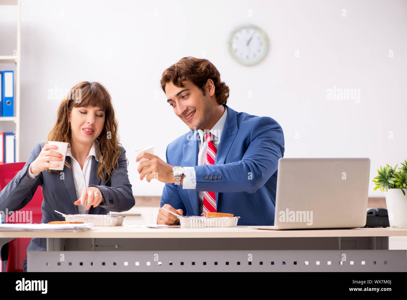 Two colleagues having lunch break at workplace Stock Photo - Alamy