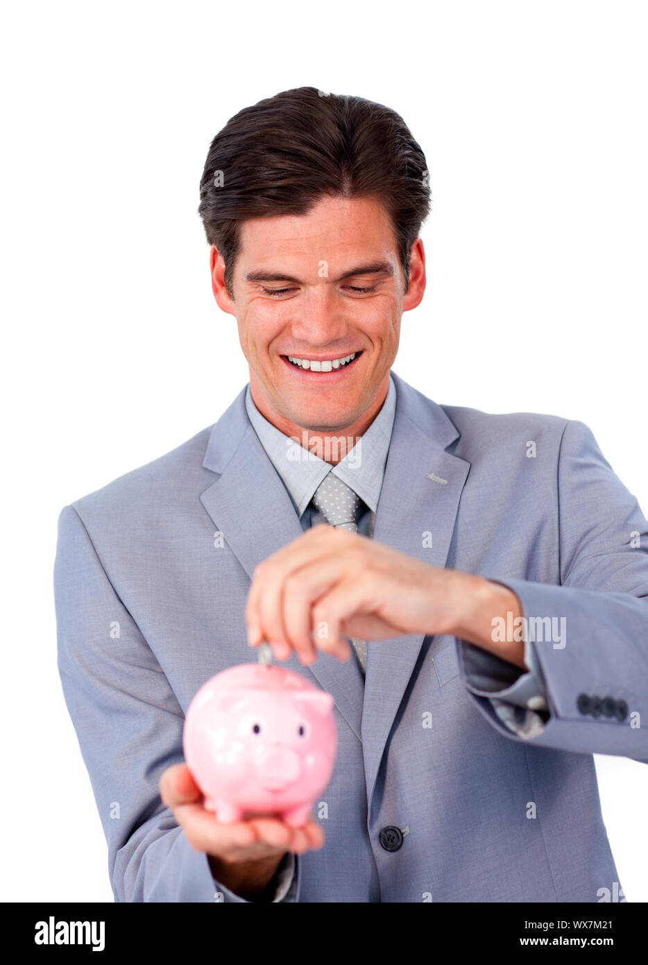Assertive businessman saving money in a piggy-bank against a white ...