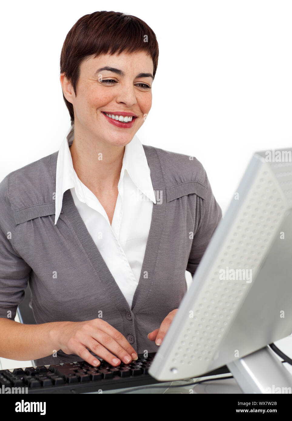 Positive female executive working at her computer against a white ...