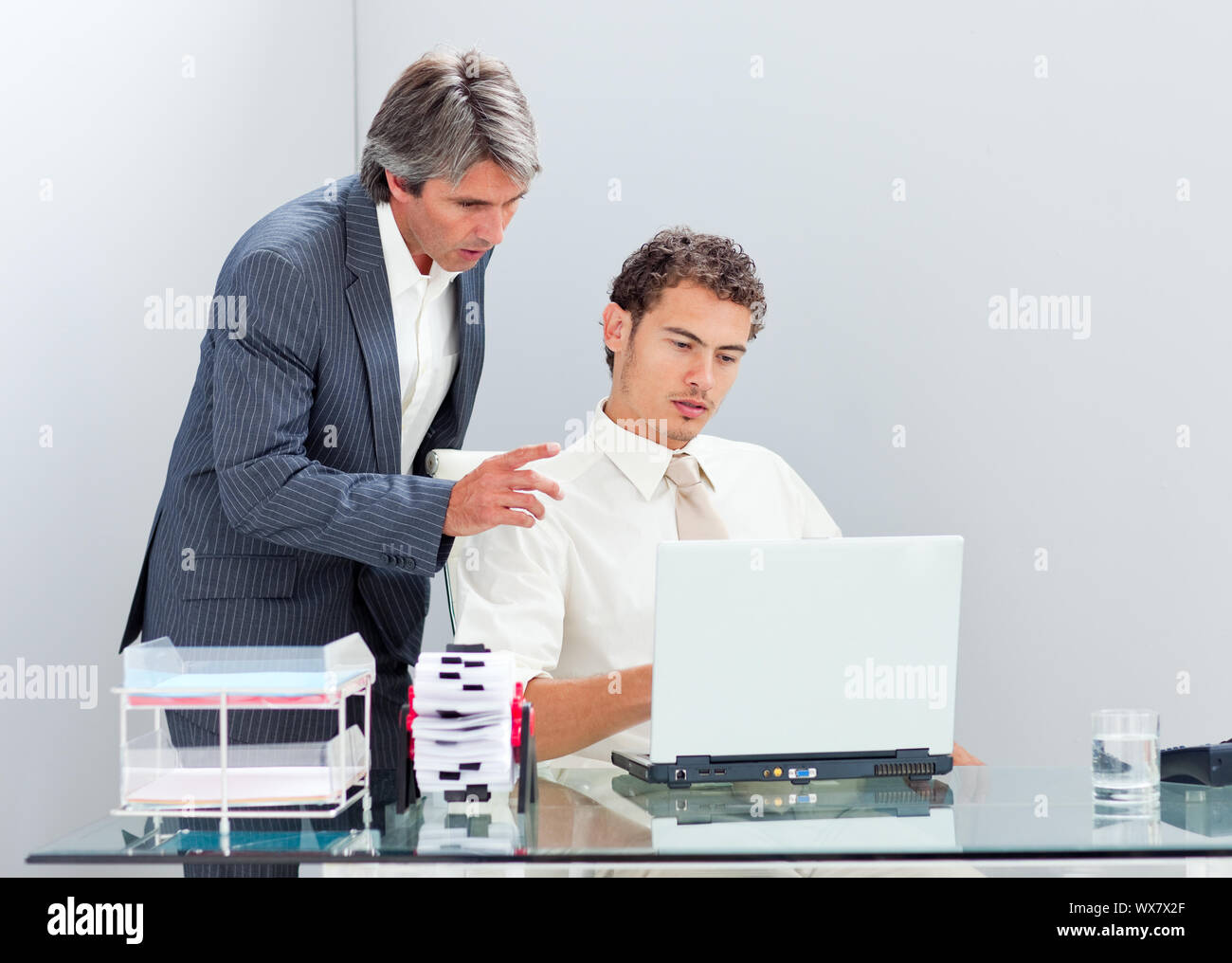 Concentrated manager helping his colleague work at a computer in the ...