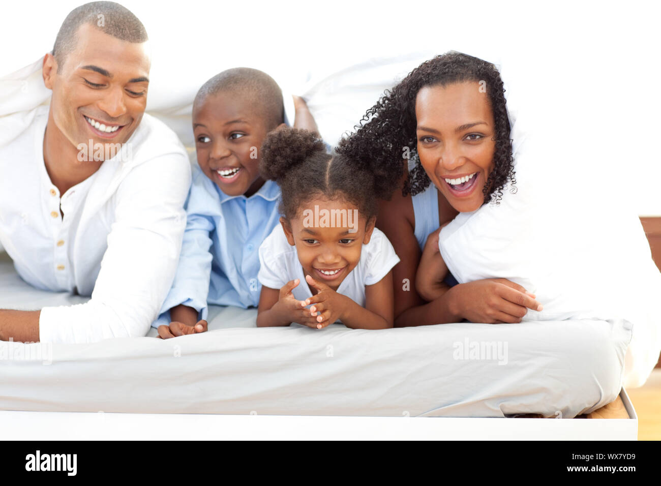 Lively family having fun lying down on bed at home Stock Photo - Alamy