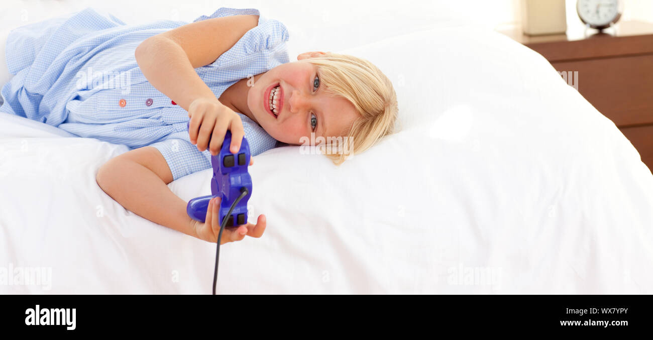 Adorable little girl playing video game lying on bed Stock Photo - Alamy