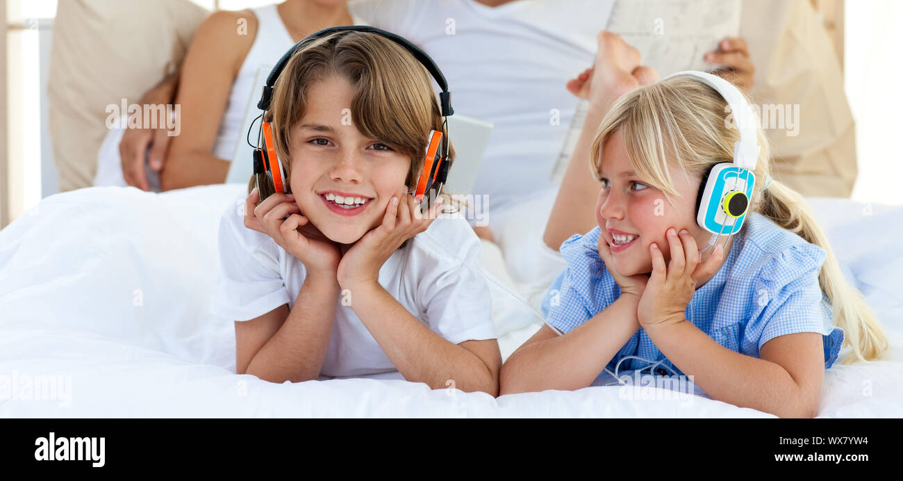 Close-up of brother and sister listening music lying on bed Stock Photo ...