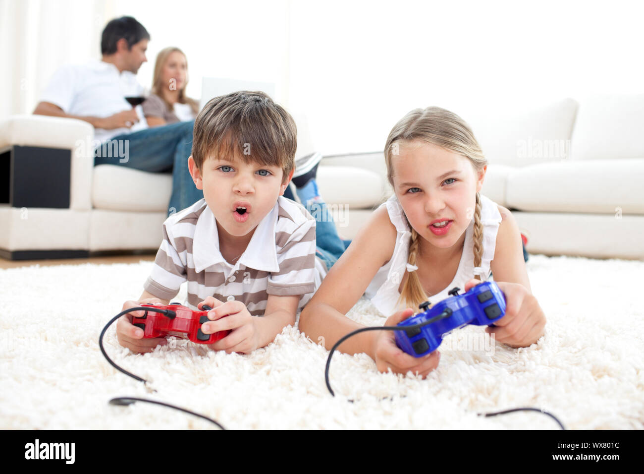 Lively children playing video games lying on the floor Stock Photo - Alamy