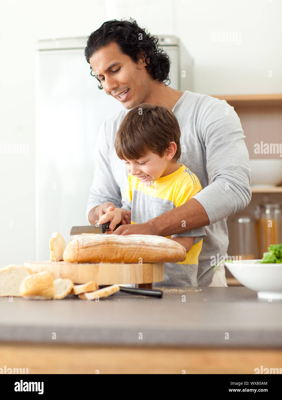 Attentive father helping his son cut some bread in the kitchen Stock ...