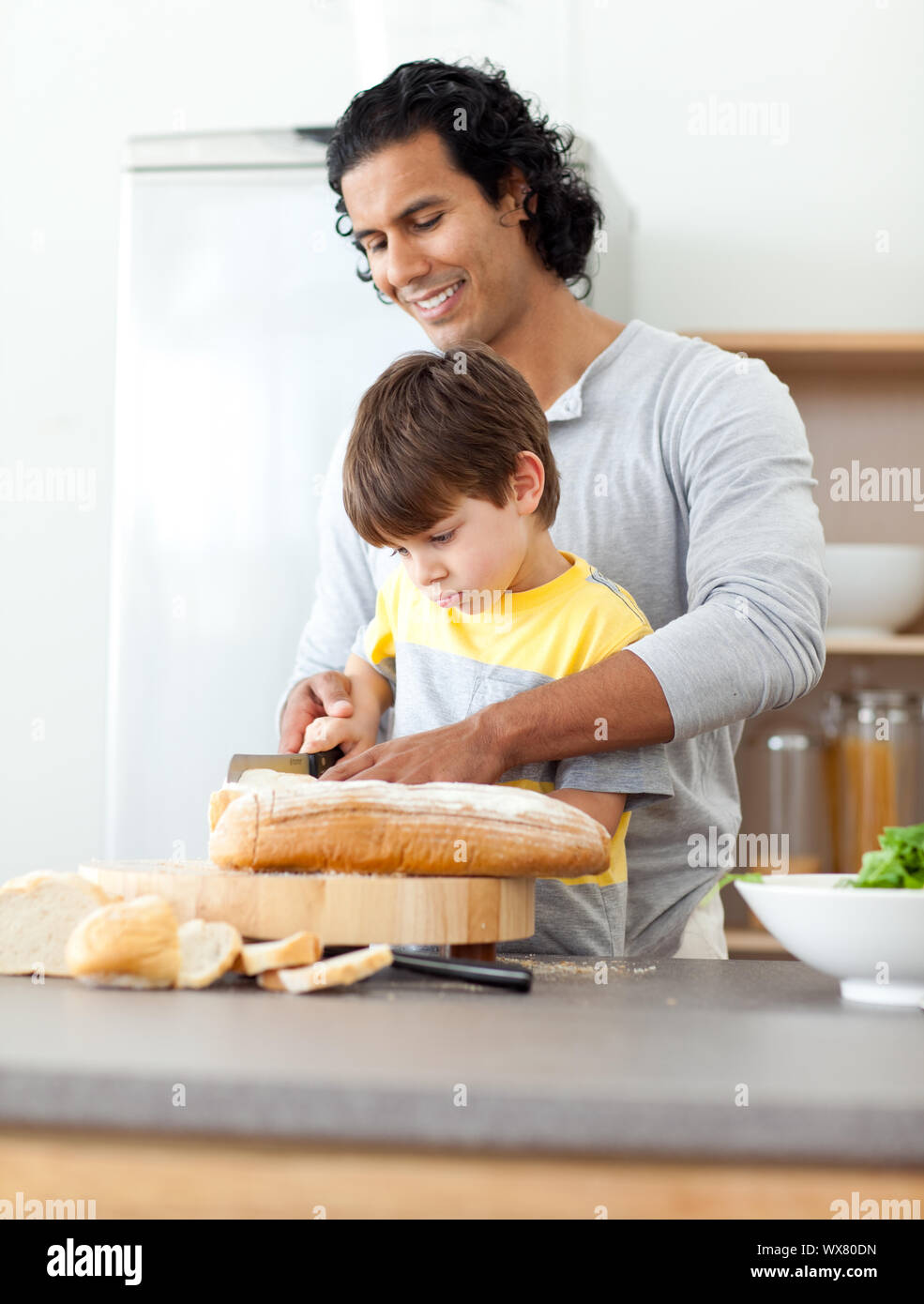 Charming father cutting bread with his son in the kitchen Stock Photo ...