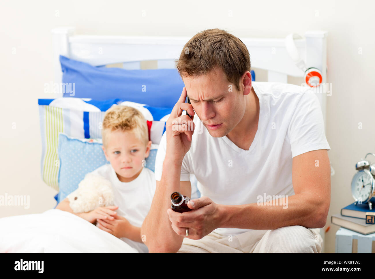 Attentive father on phone giving syrup to his son sitting on bed Stock ...