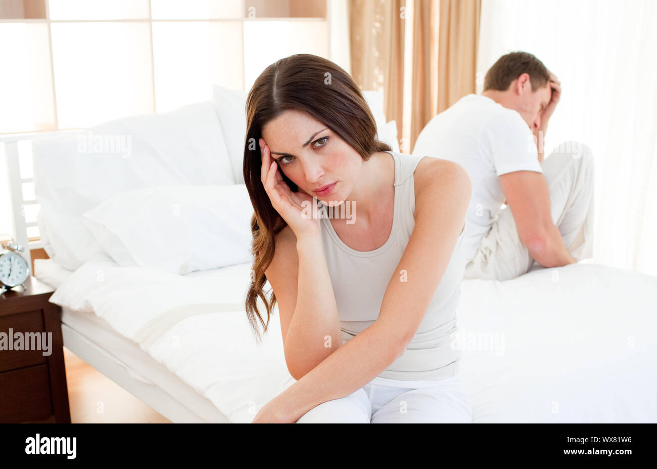 Upset Couple Sitting Separately On Their Bed After An Argument Stock