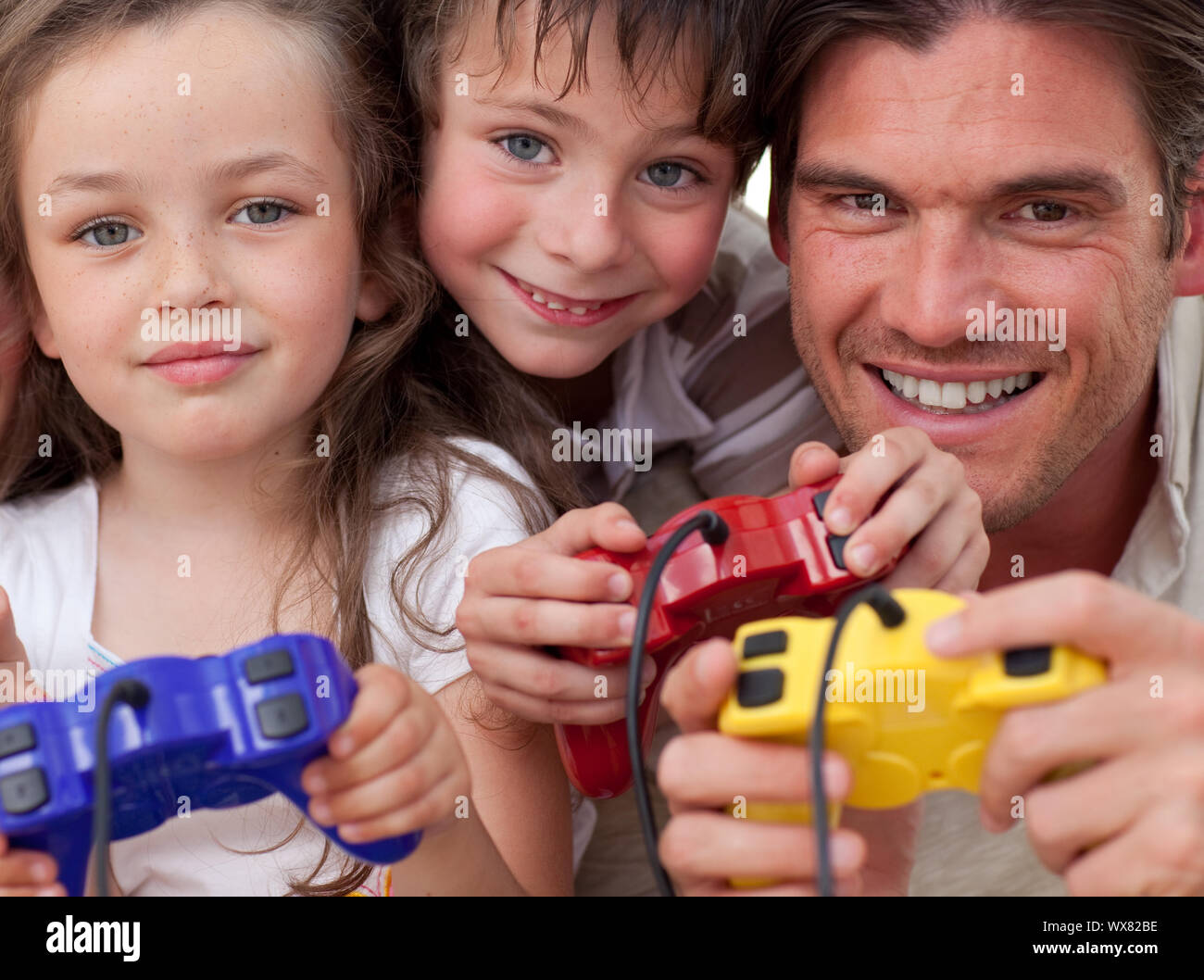 Happy father and his children playing video games at home Stock Photo ...