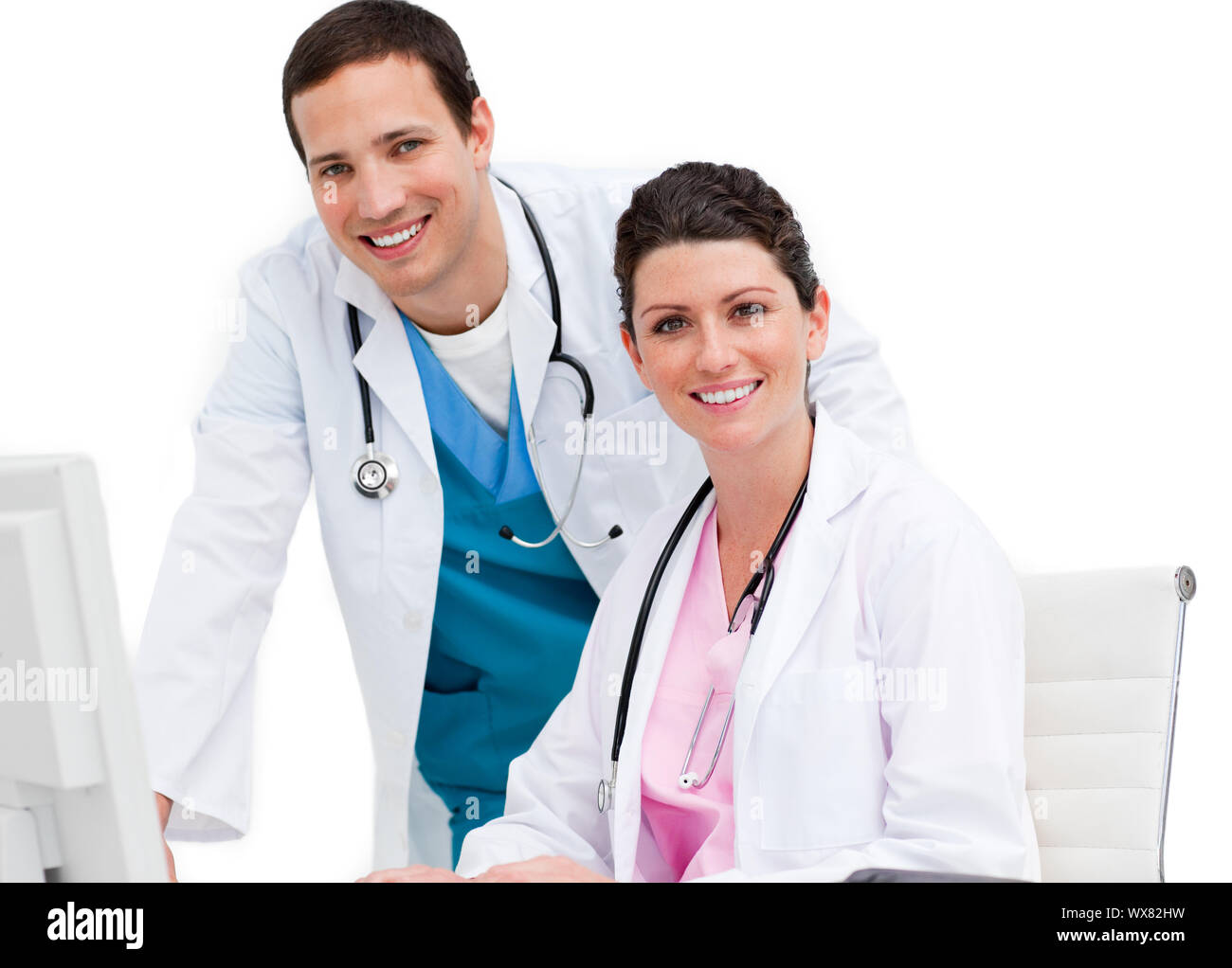 Two smiling doctors working at a computer against a white background ...
