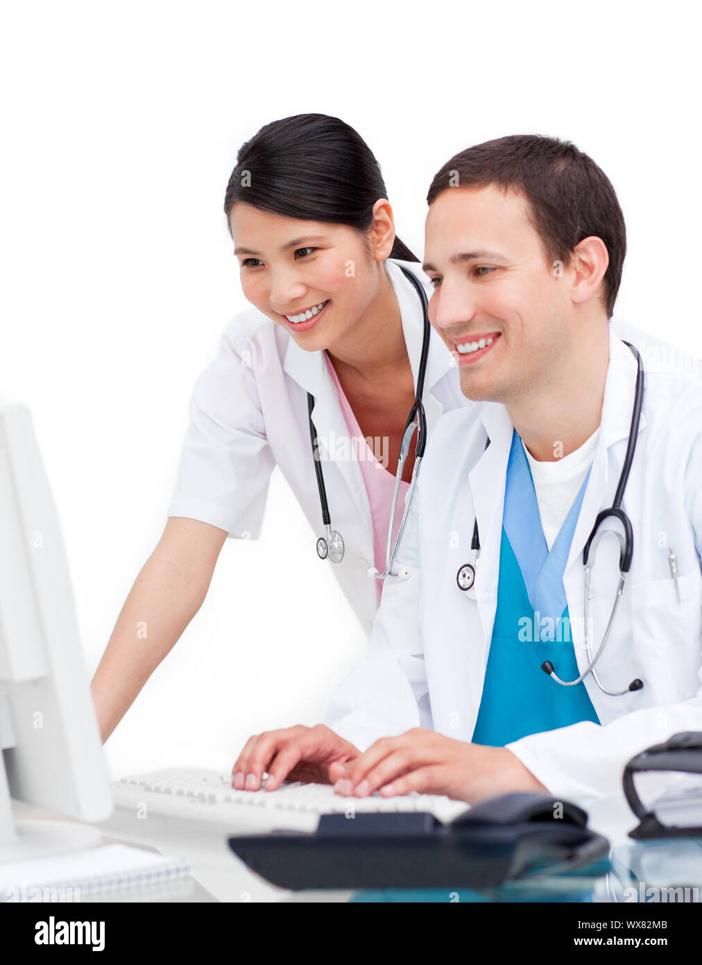 Two happy doctors working at a computer against a white background ...