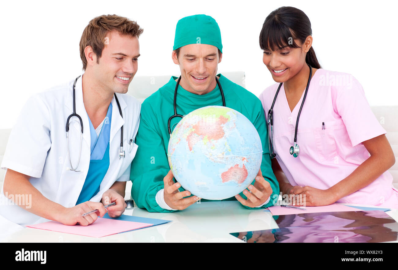 Cheerful medical team looking at terrestrial globe against a white ...