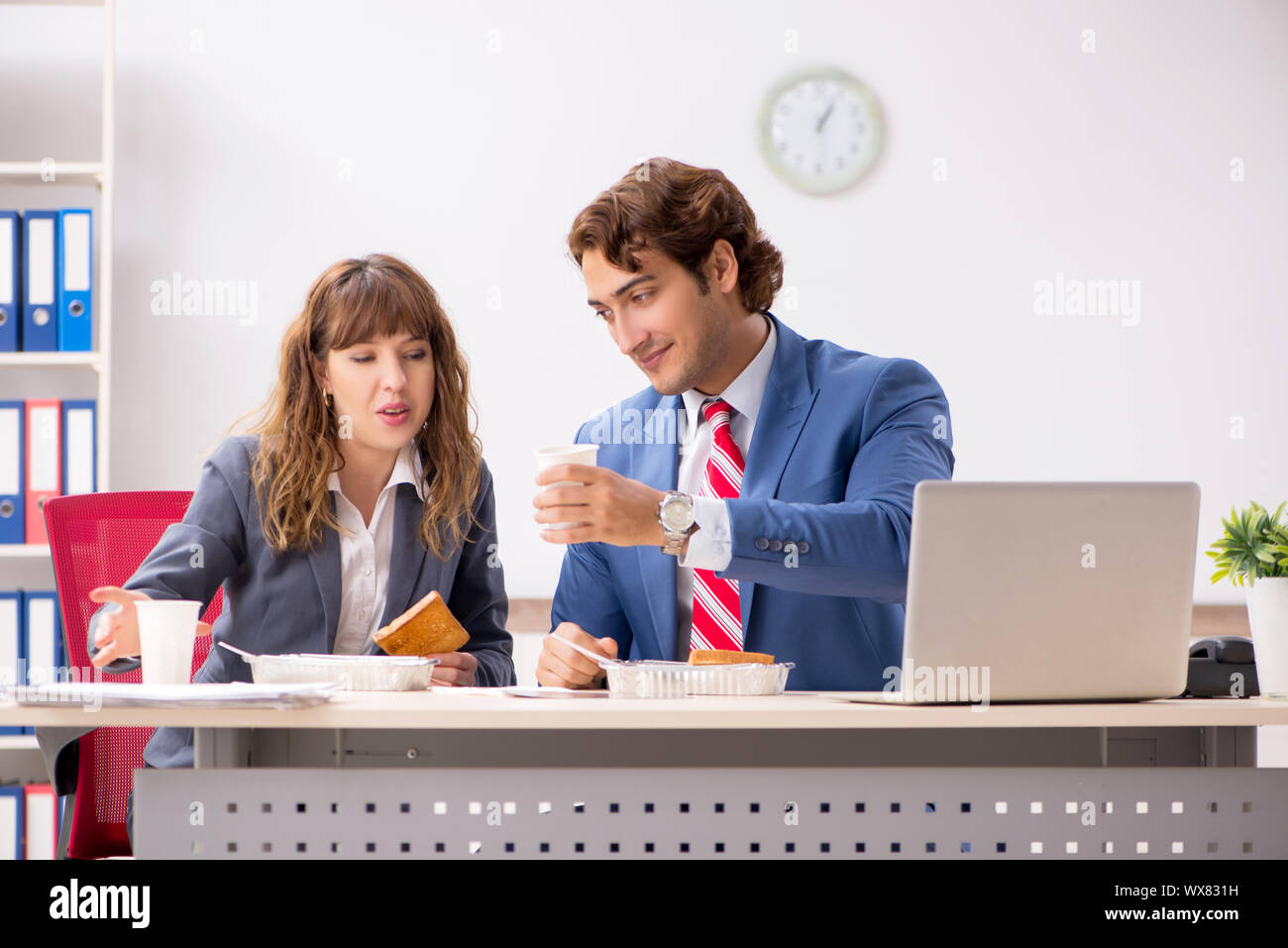 Two colleagues having lunch break at workplace Stock Photo - Alamy