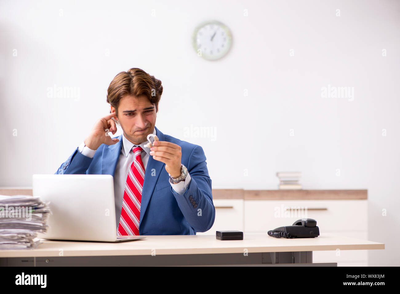 Deaf employee using hearing aid in office Stock Photo - Alamy
