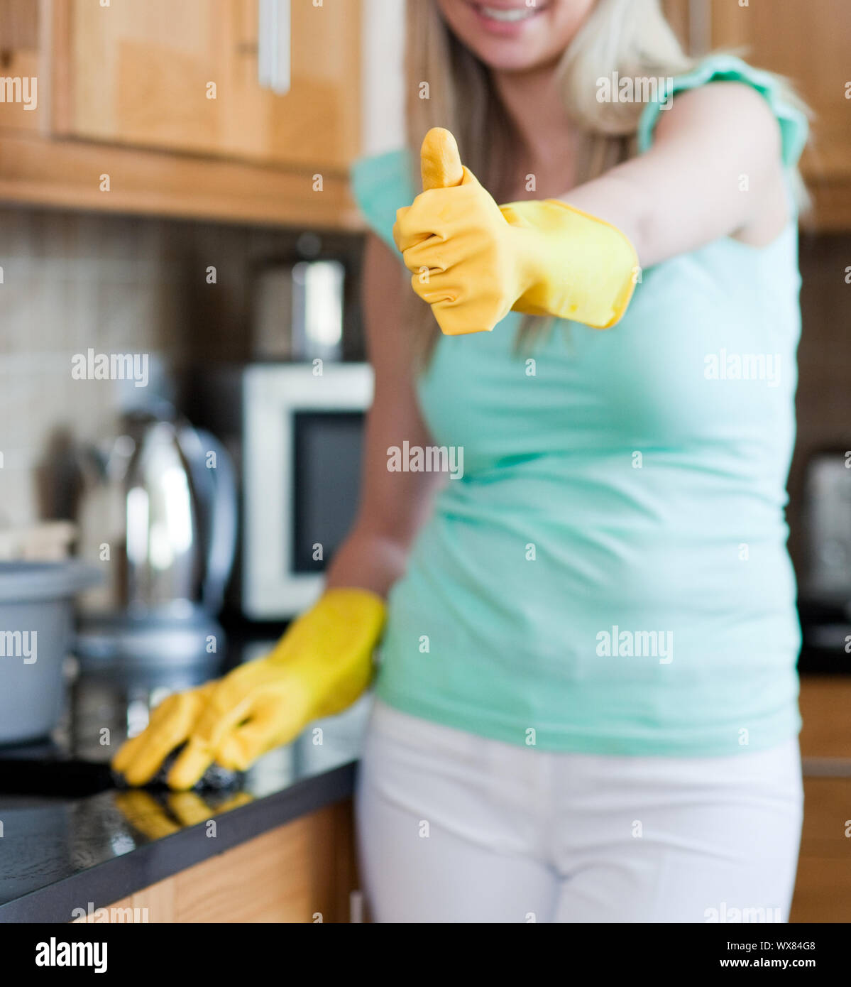 Smiling woman with thumb up cleaning a kitchen at home Stock Photo - Alamy