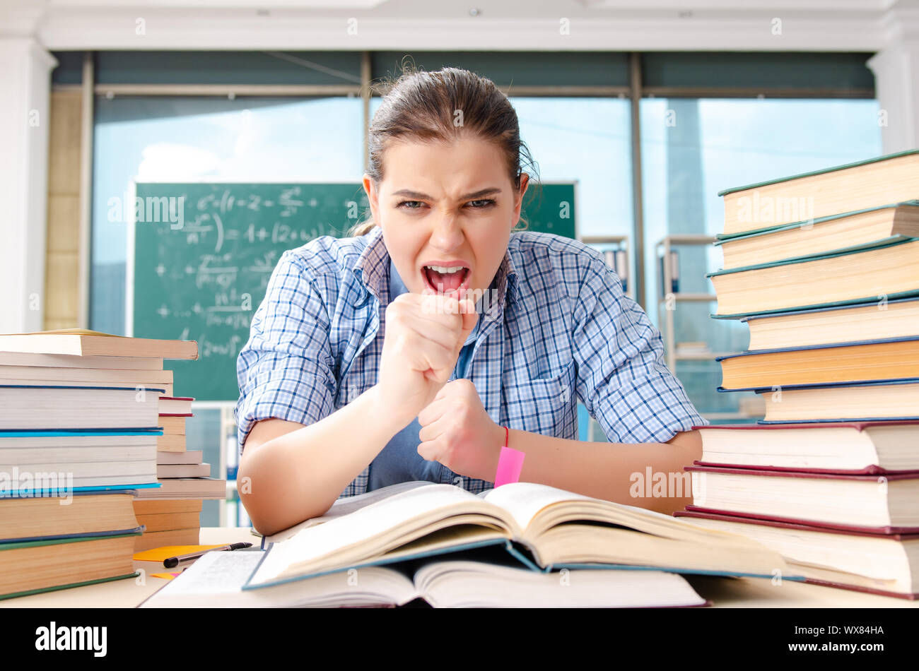 Female student with many books sitting in the classroom Stock Photo - Alamy