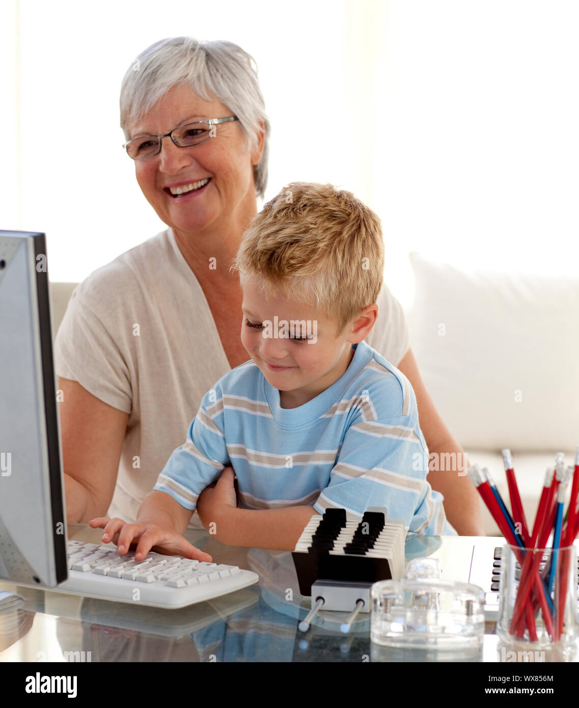 Grandson using a computer with his grandmother at home Stock Photo - Alamy
