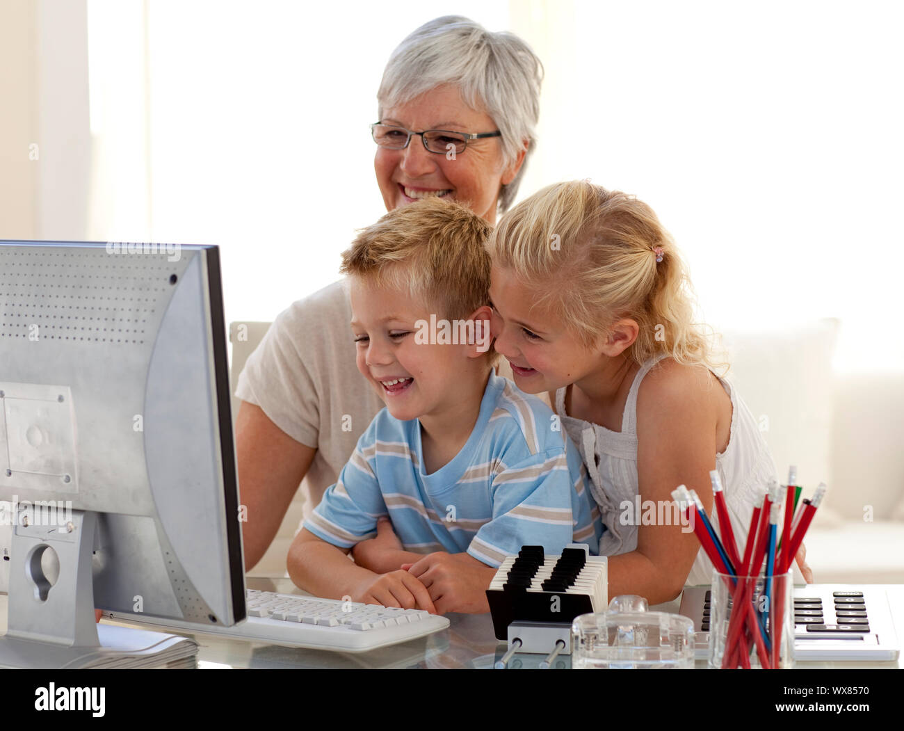 Children using a computer with their grandmother at home Stock Photo ...