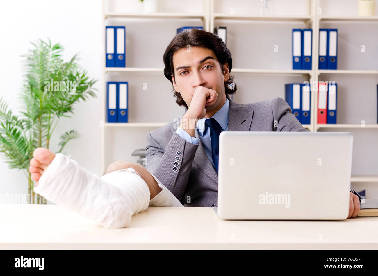 Leg injured employee working in the office Stock Photo - Alamy