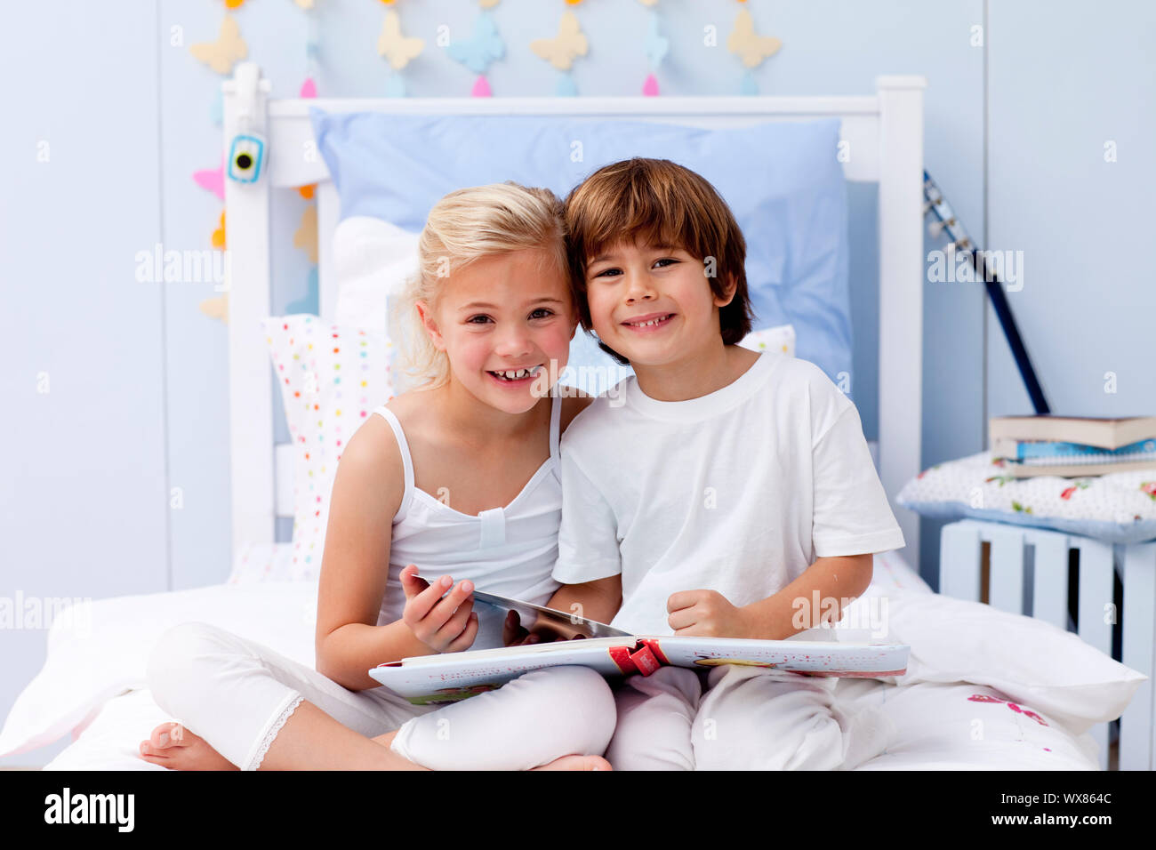 Smiling children reading a book in bedroom Stock Photo - Alamy