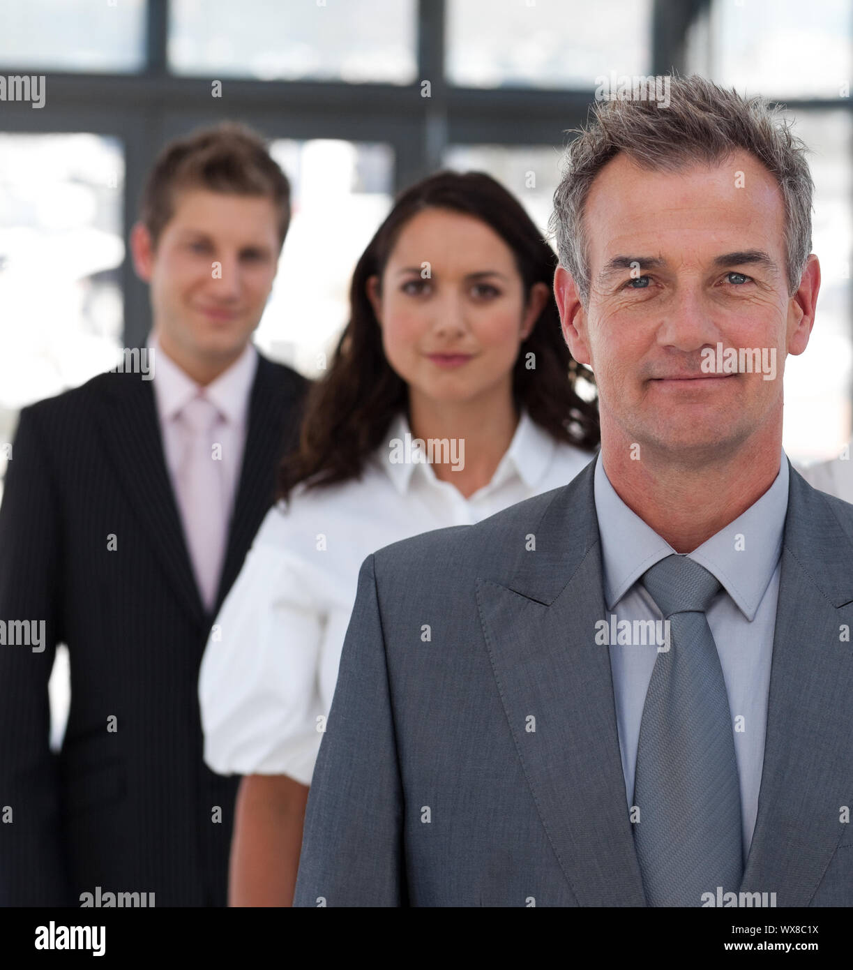 Mature businessman leading a business team in a line Stock Photo - Alamy