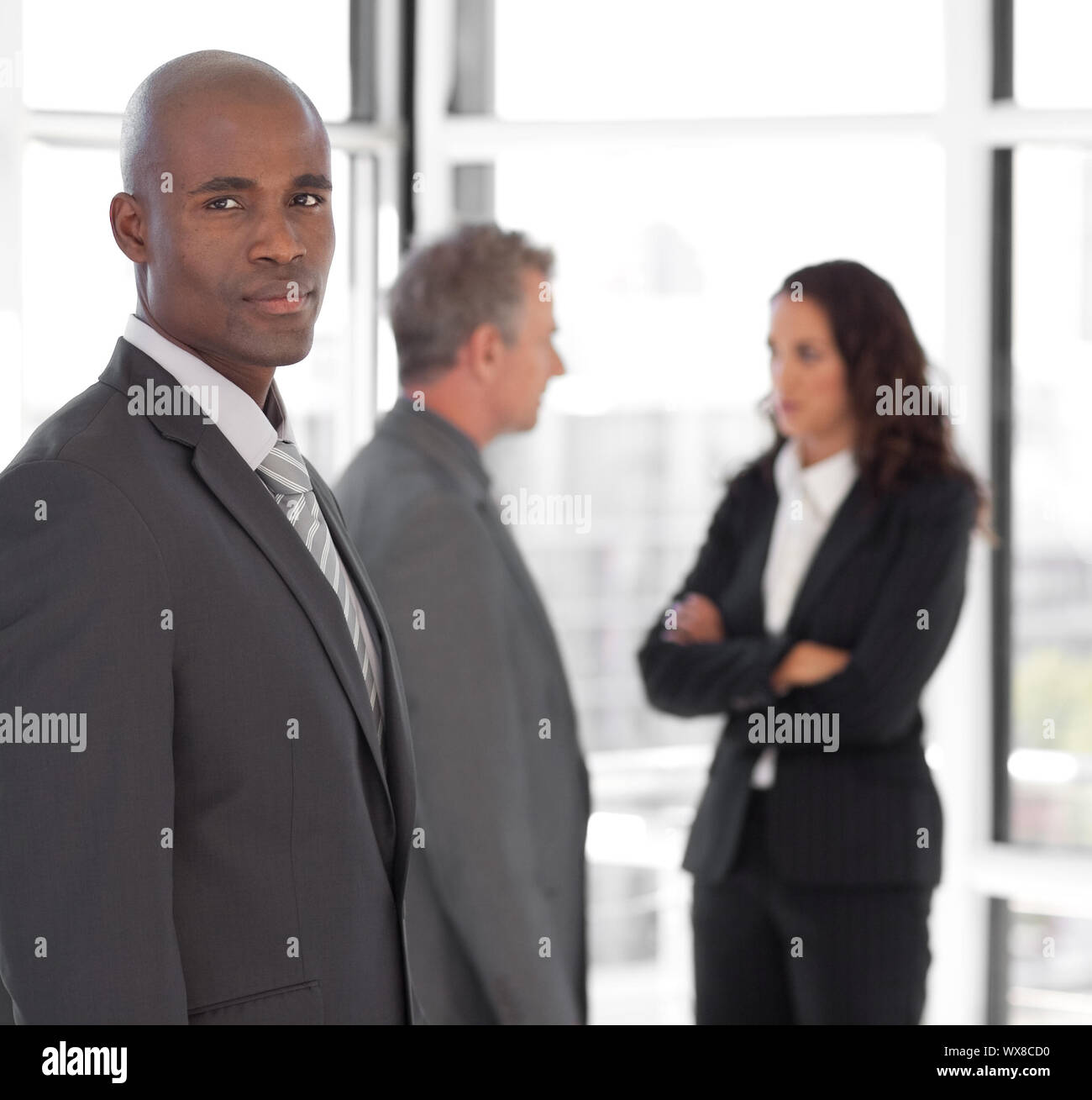 Serious business leader looking at camera in front of team Stock Photo ...