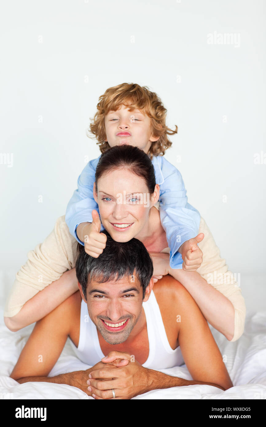 Bright family lying on a white bed Stock Photo - Alamy