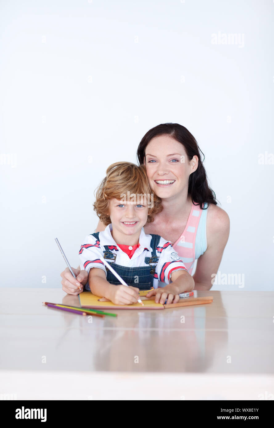 Mother and son writing at home and smiling to the camera Stock Photo ...