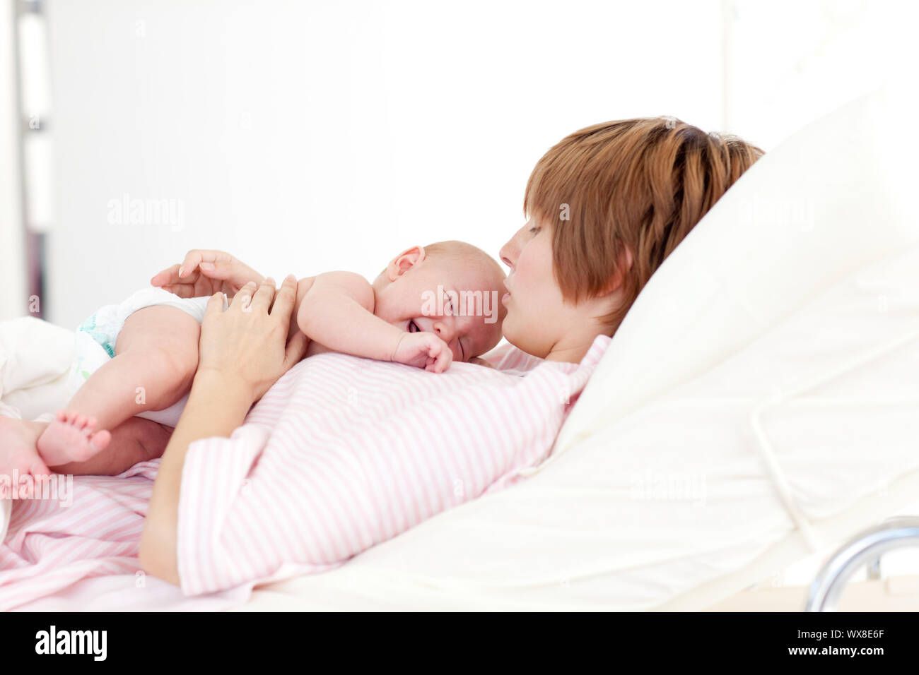 Woman kissing her newborn baby in hospital Stock Photo - Alamy