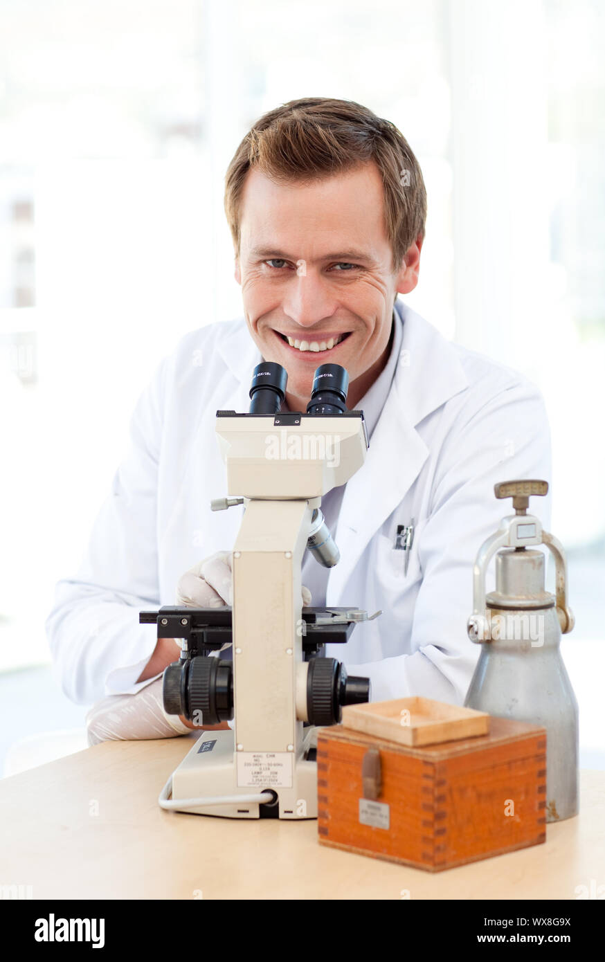 Smiling scientist looking through a microscope in a laboratory Stock ...