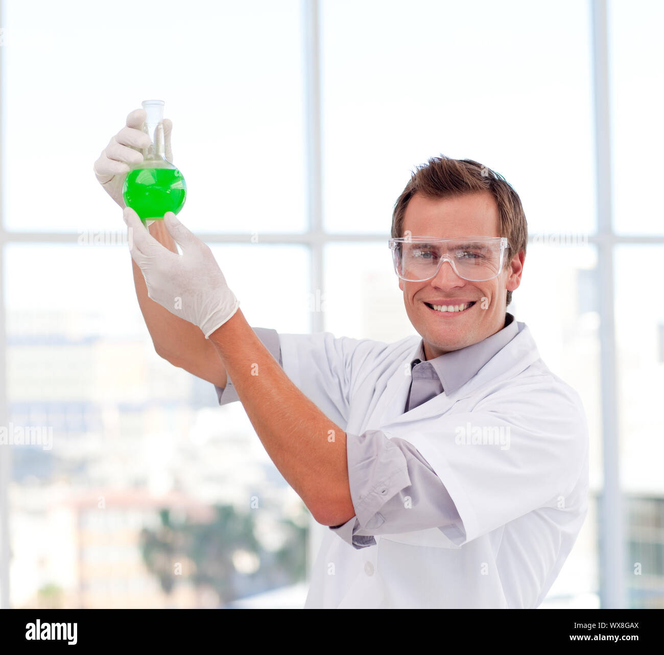 Scientist examining a test-tube in a laboratory smiling at the camera ...