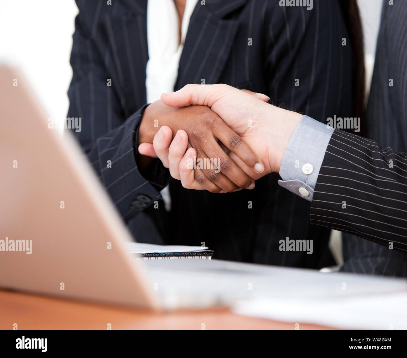 Close-up of a handshake between two businessmen with laptop in the ...