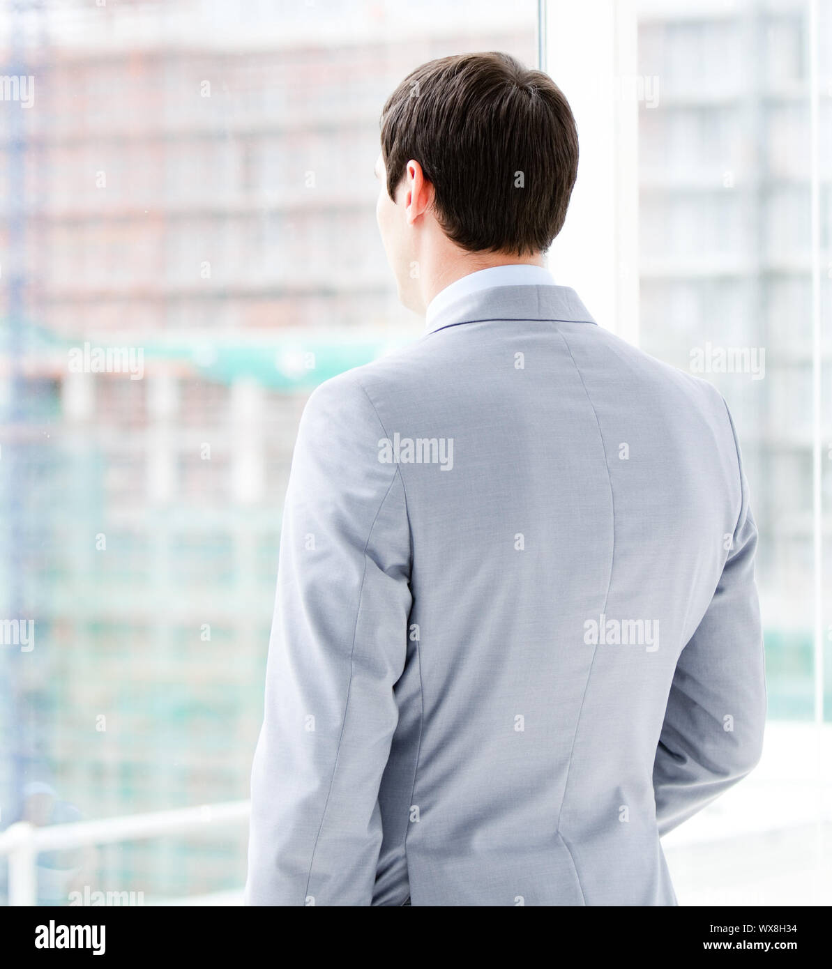 Thinking businessman looking through a window in the office Stock Photo ...