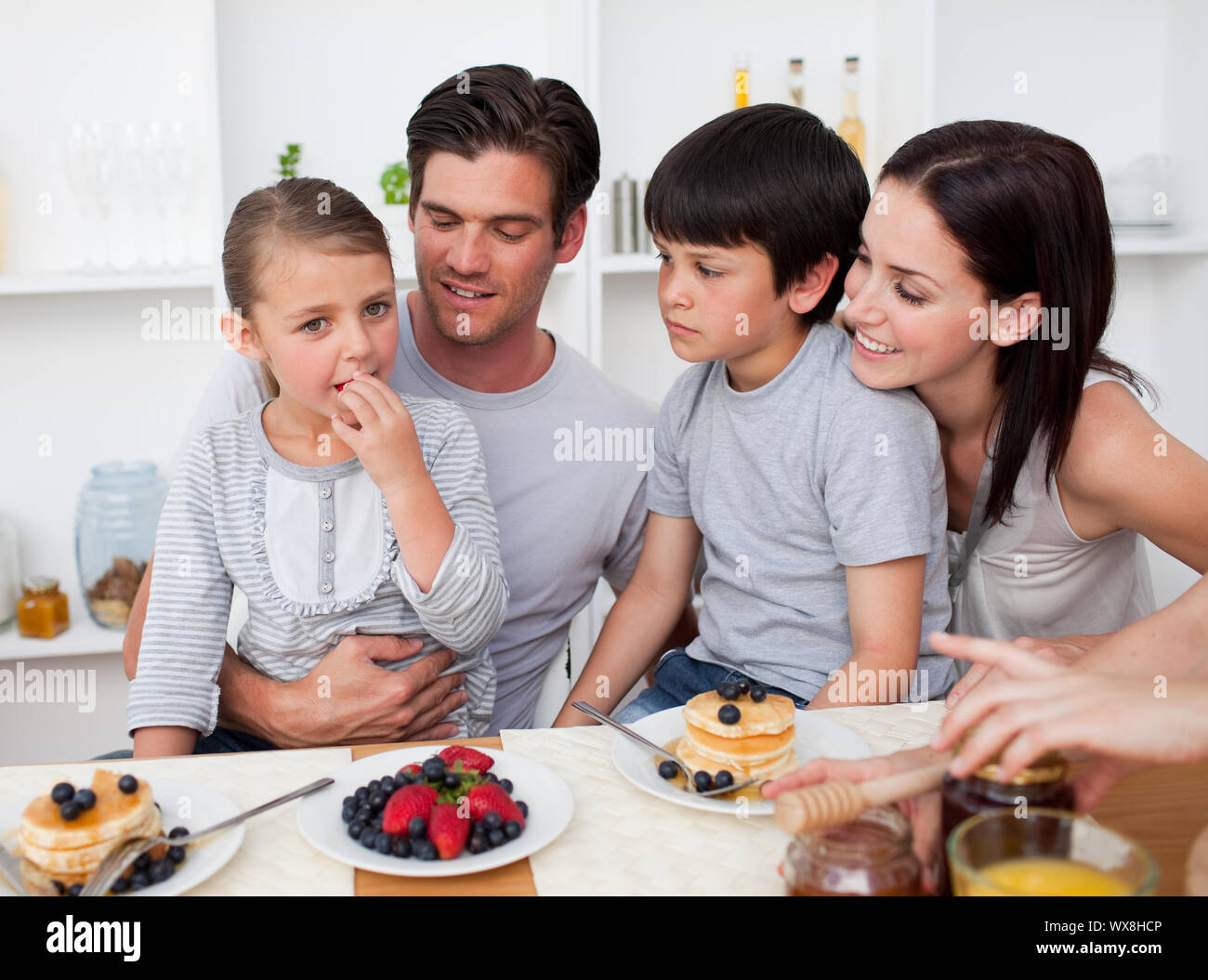 Smiling family eating pancakes for breakfast in the kitchen Stock Photo ...