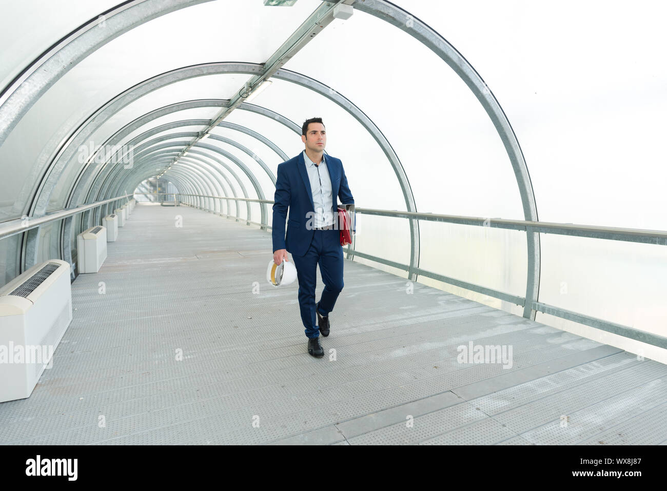suited man walking along arched walkway Stock Photo - Alamy