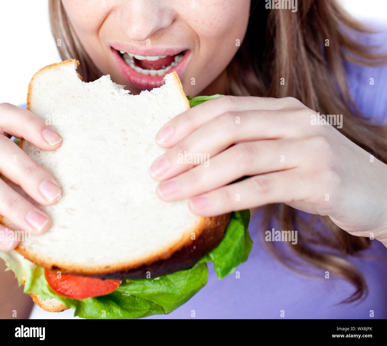 Close-up of a woman eating a sandwich isolated on a white background ...