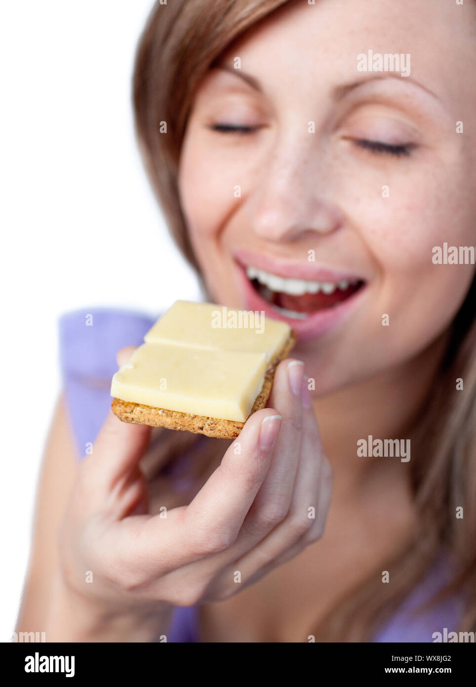 Young woman eating a cracker with cheese isolated on a white background ...