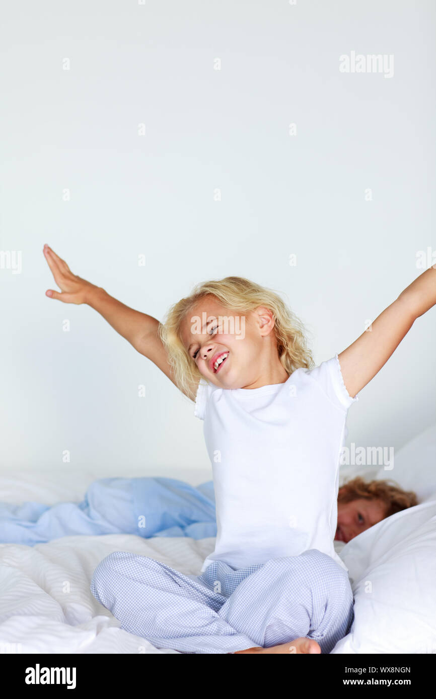 Tired girl stretching on the bed against white background Stock Photo ...