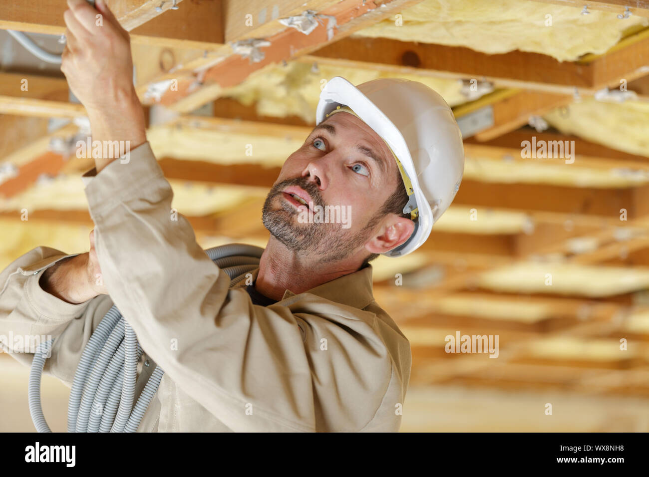 electrician passing cables through roof timbers Stock Photo - Alamy