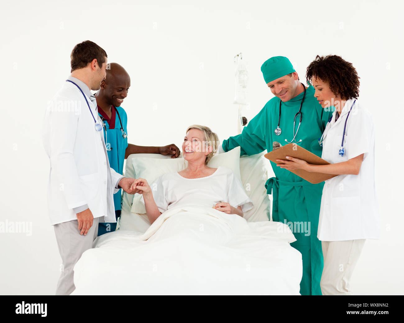 Elderly smiling patient between a medical team against white background ...