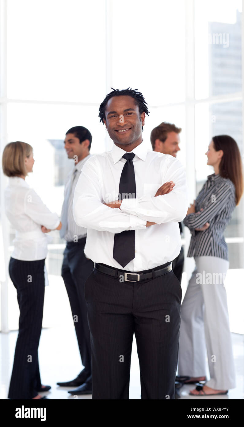 African male manager standing at the camera with his team in a office ...