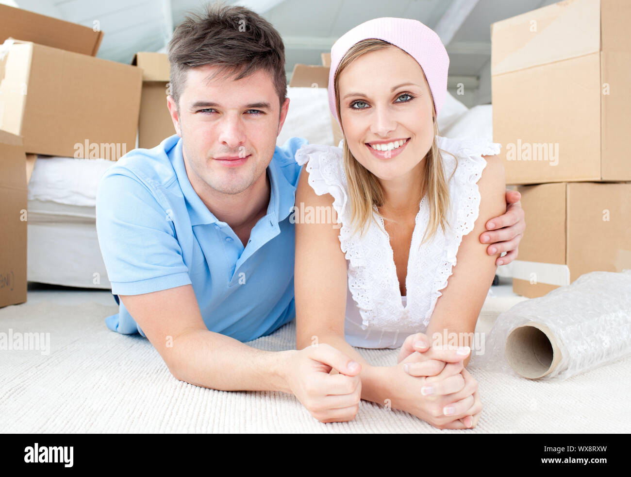 Jolly couple lying between boxes in their new house Stock Photo - Alamy